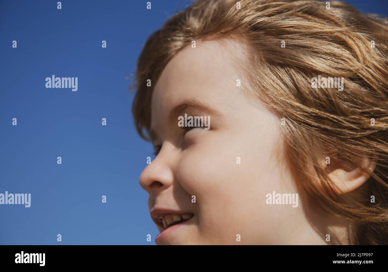 Portrait of little boy looking away on blue sky with copy space, face ...