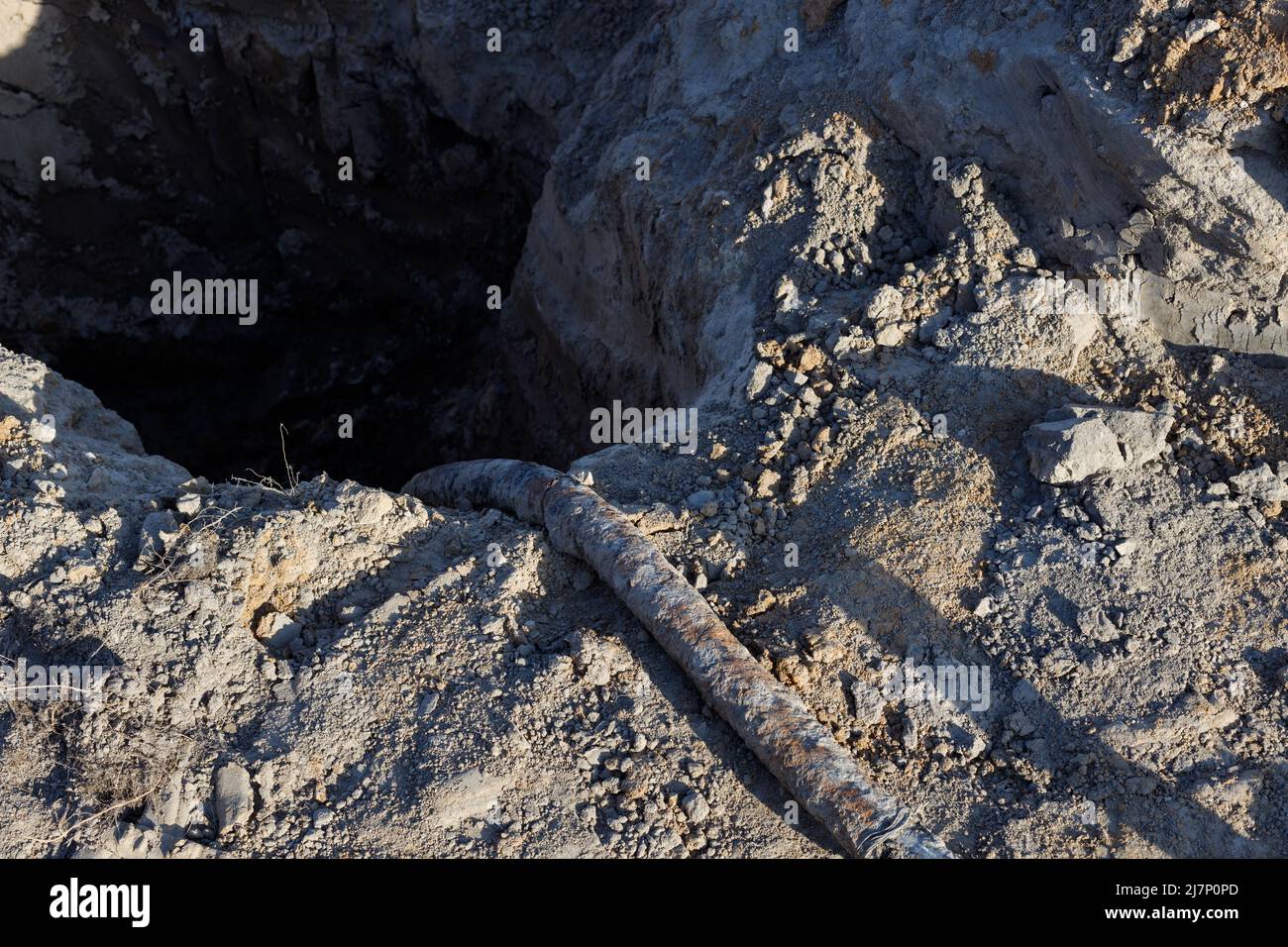 Rusty, thick and old earth cable. Old installation, trench in the ...