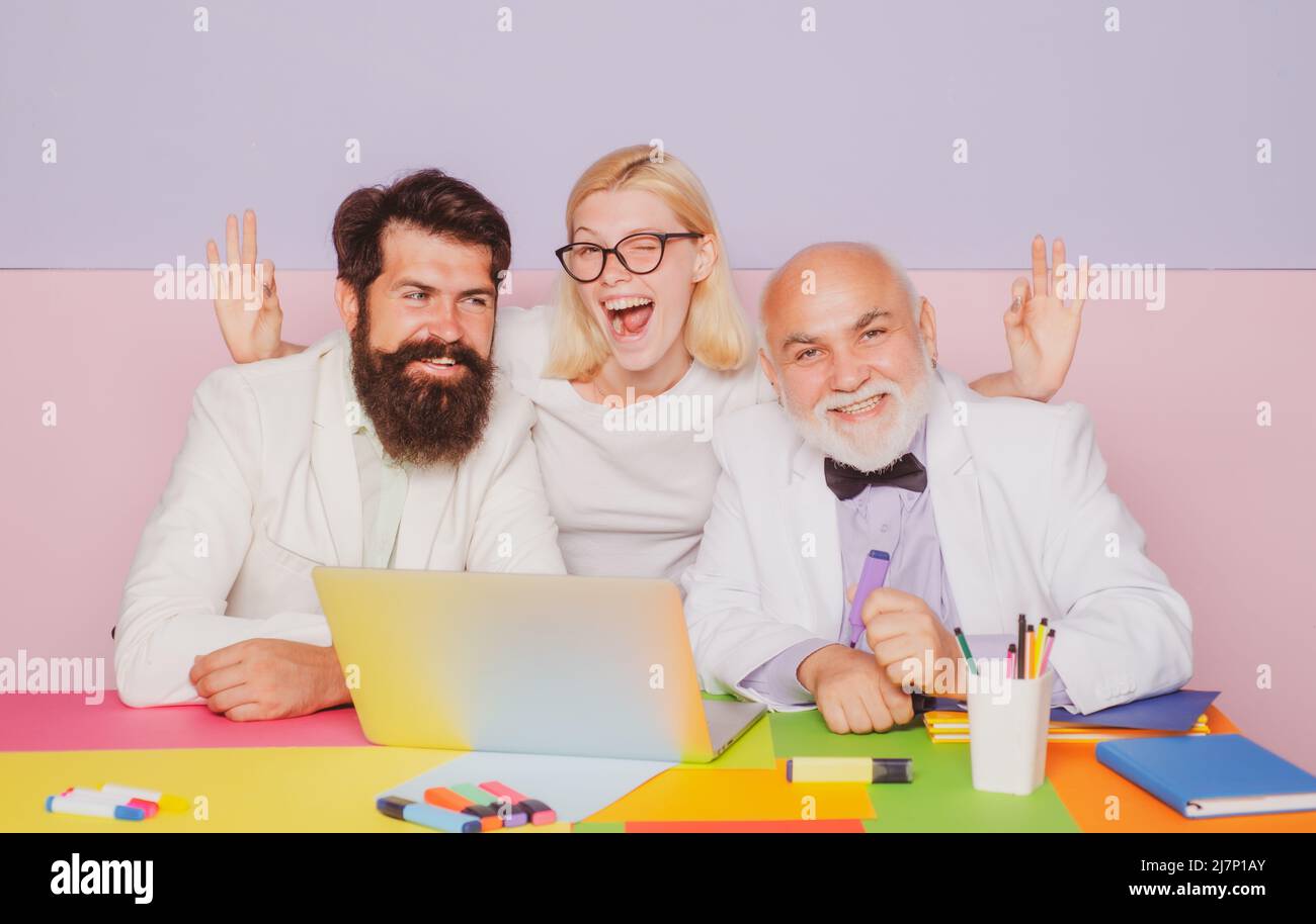 Funny excited business team sitting by the table with laptops ...