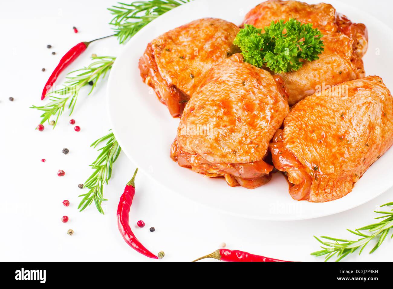 Chicken thighs marinated in red sauce on a white plate,on white ...