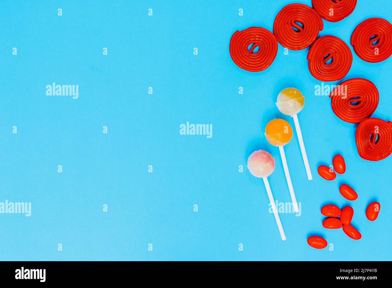 red candies and lollipops on a plain blue background. wallpaper to use ...