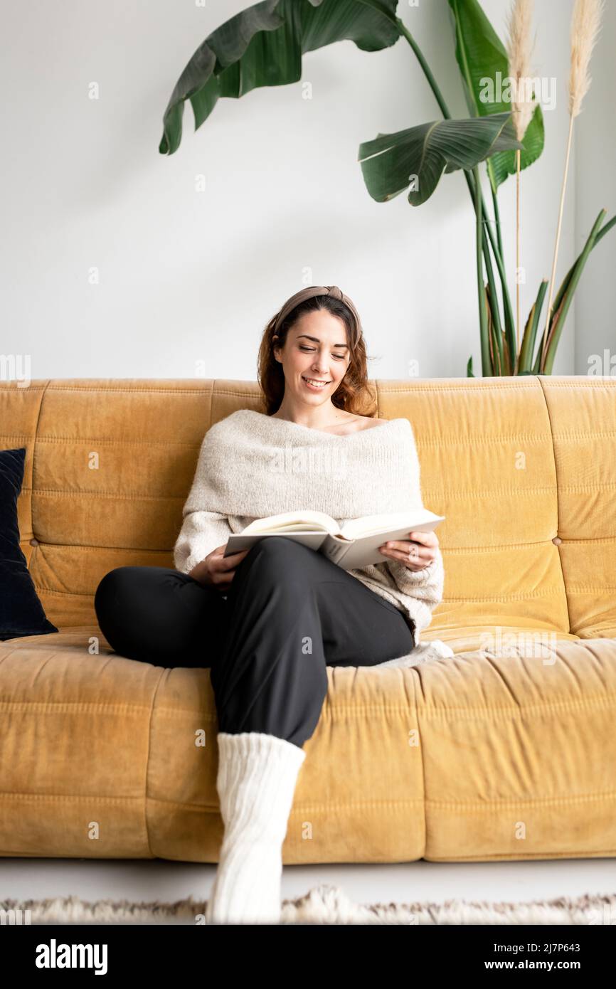 Beautiful girl on a sofa reading a book Stock Photo - Alamy