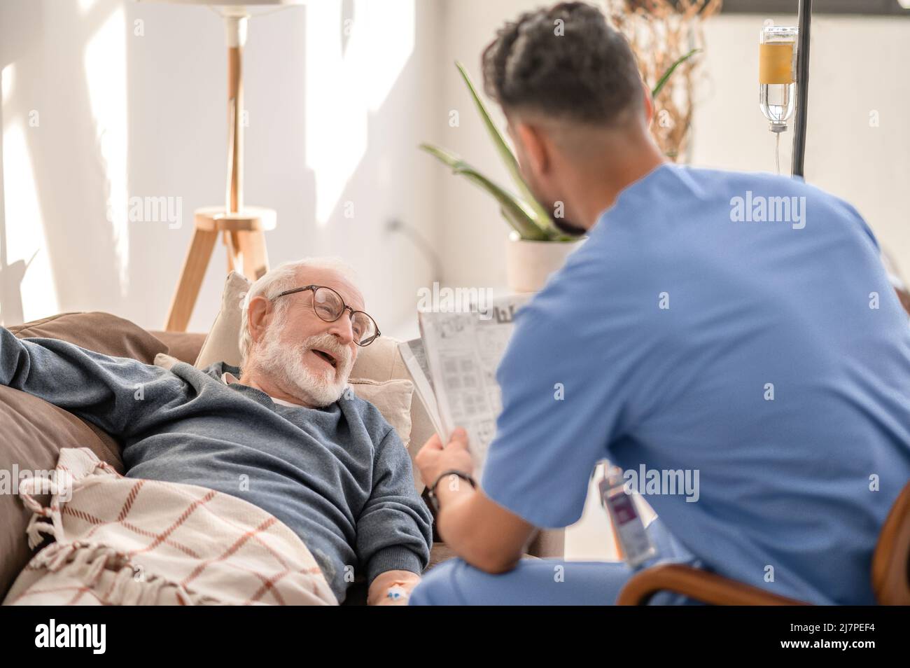 Caring caregiver entertaining male patient during the intravenous ...