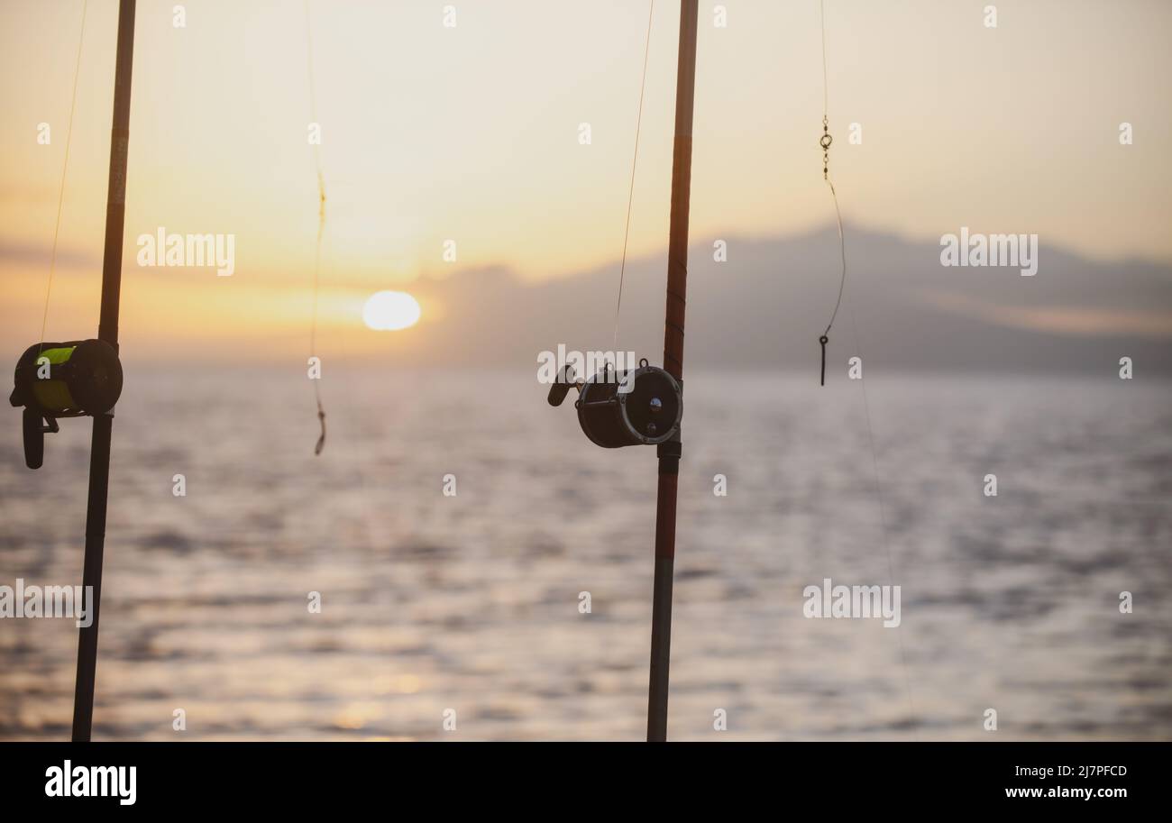 Fishing rod and reel on the sea and sunset sky Stock Photo - Alamy