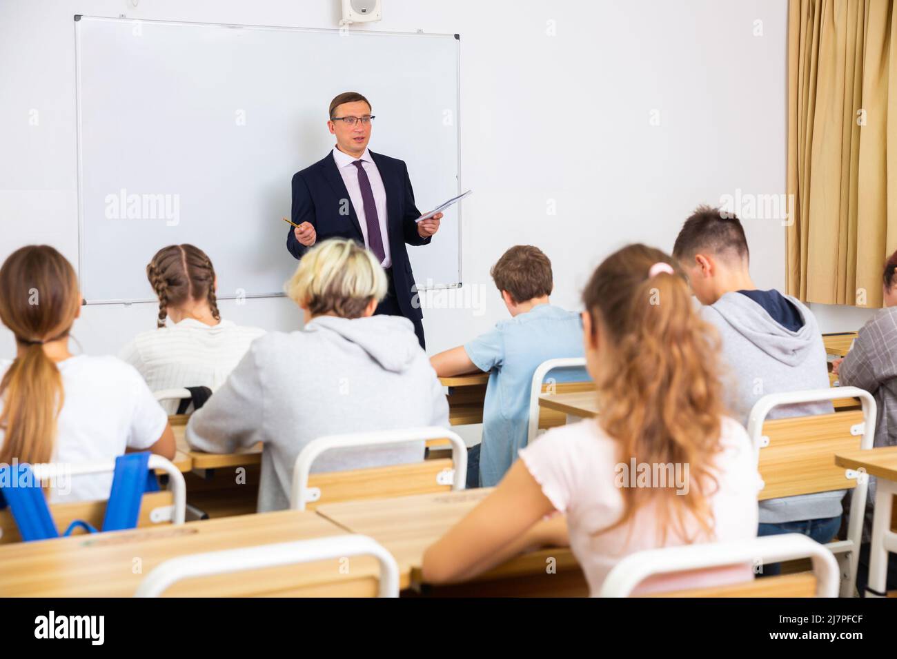 Adult teacher is giving lecture for students in class Stock Photo - Alamy