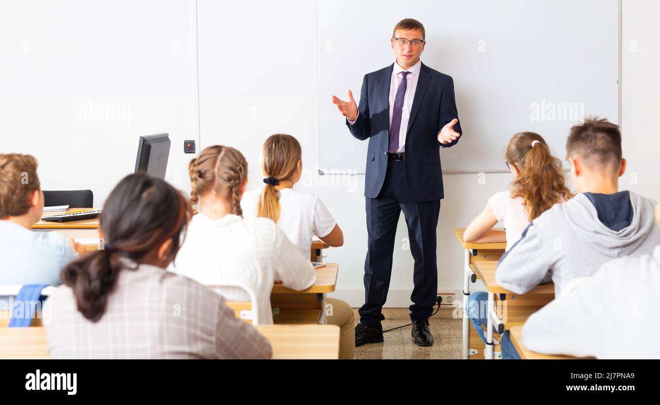 Man teacher with notebook is giving interesting lecture for students in ...