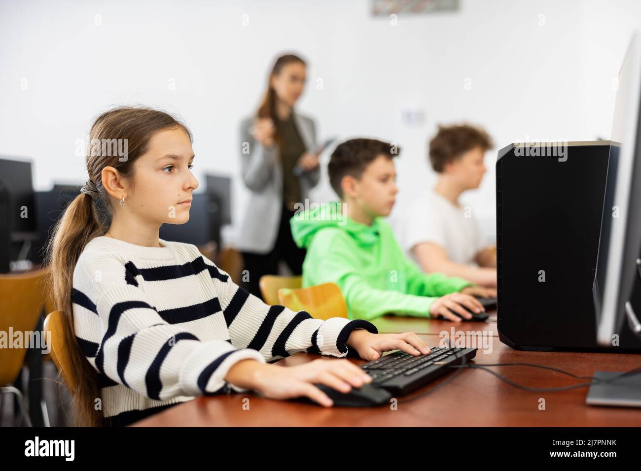 Teen schoolgirl learning basics of programming in computer college ...