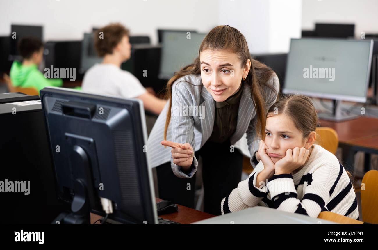 Teacher helping sad girl to solve computer problem Stock Photo - Alamy