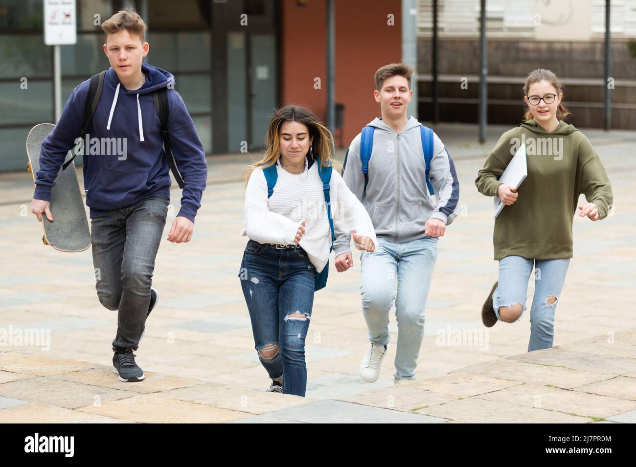 Cheerful teenagers running on city street Stock Photo - Alamy
