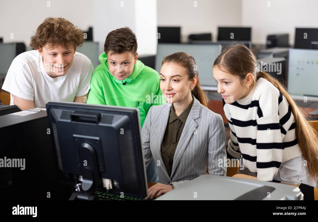 Teacher helping young student in computer class Stock Photo - Alamy