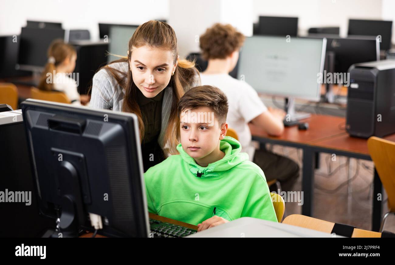 Teacher explaining task solution to pupil during computer science ...