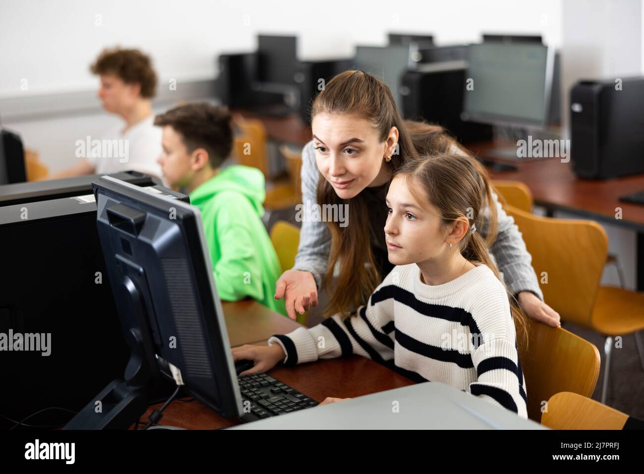 Teacher helping girl to solve computer problem Stock Photo - Alamy