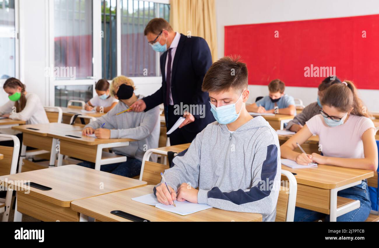 Teacher in protective mask explains to the students the subject of ...