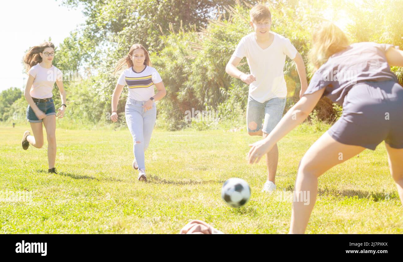 Company of glad teenagers playing football Stock Photo - Alamy