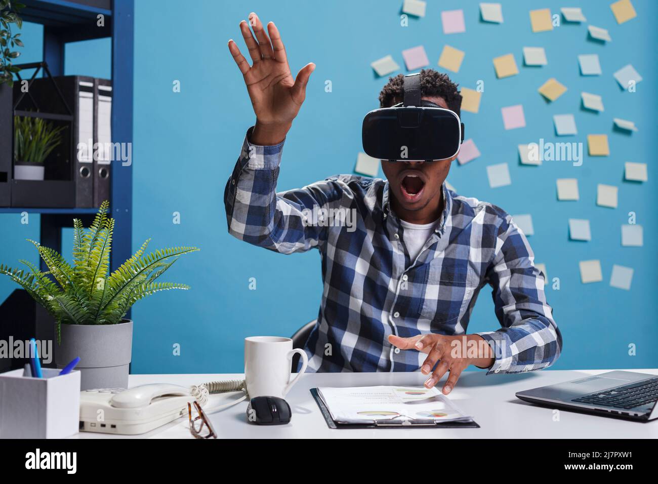 Astonished scared office worker wearing virtual reality headset while ...