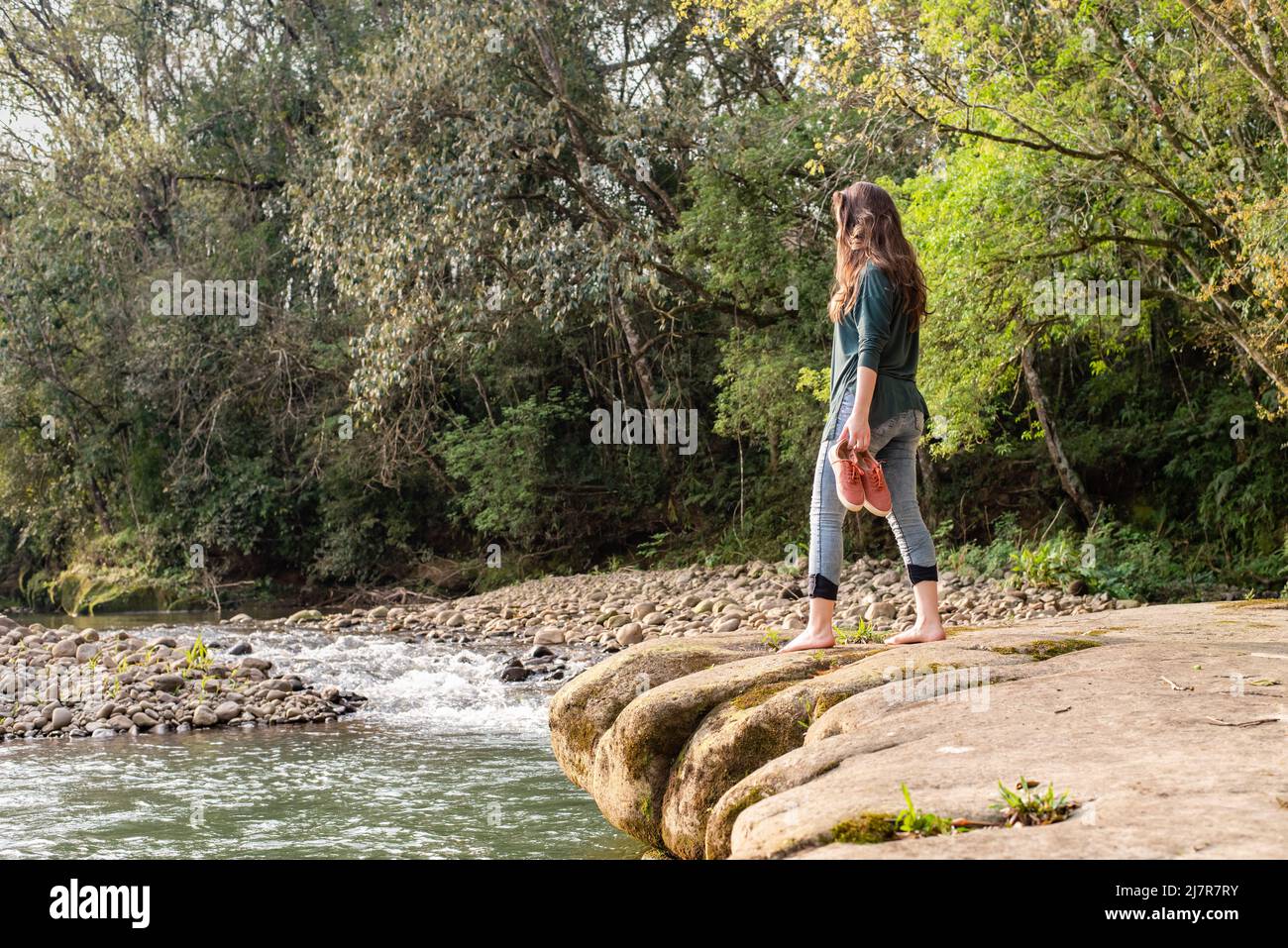 Woman walking on rocks barefooted with her shoes in hands Stock Photo ...