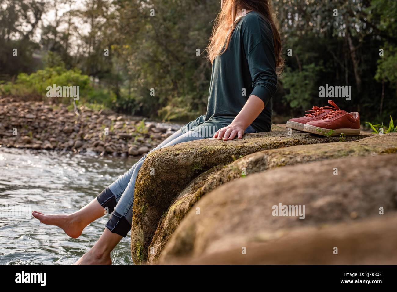 Woman's feet dangling from river Stock Photo - Alamy