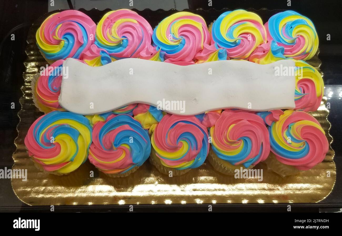 A bunch of colorful cupcakes with white icing strip on top Stock Photo ...