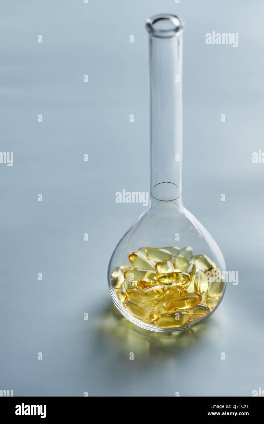 Omega-3 fatty acid capsules on a blue background in a flask. The ...