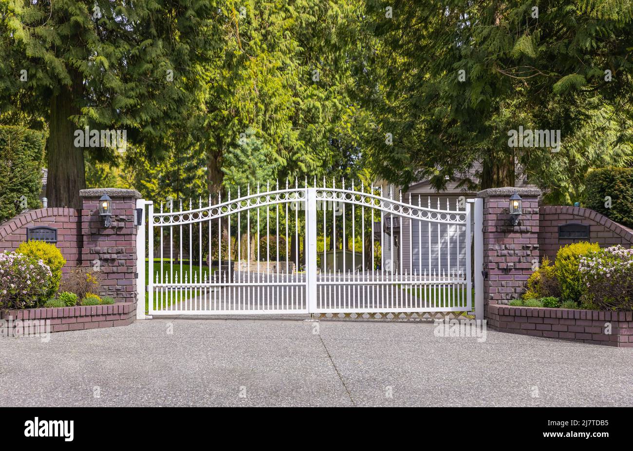 Iron front gate of a luxury home. Wrought iron white gate and brick ...