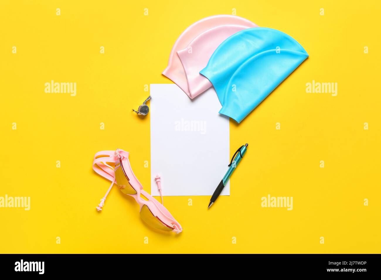 Paper sheet with swimming caps, goggles, whistle and pen on yellow ...