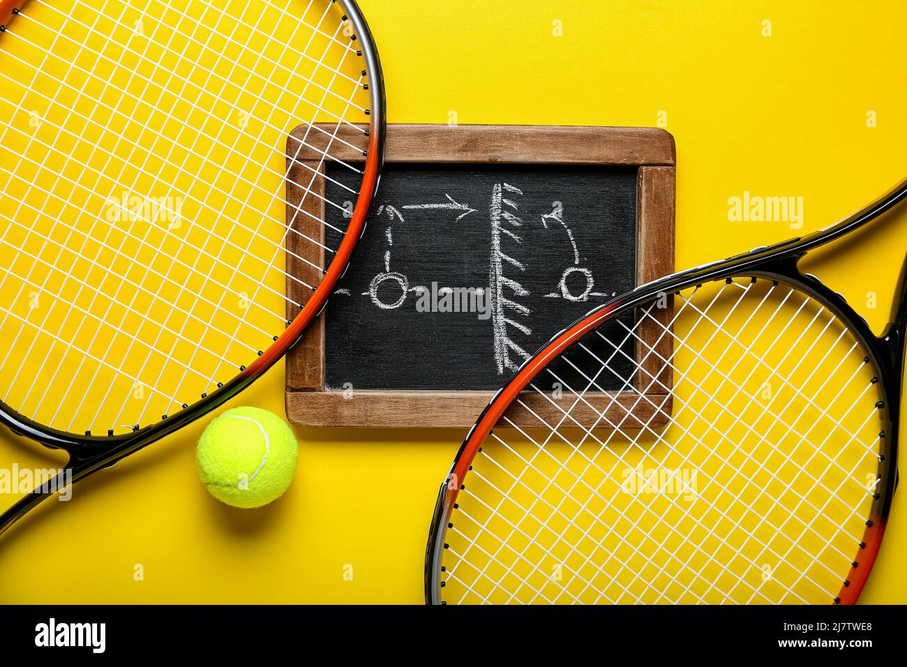 Chalkboard with drawn scheme of tennis game, ball and rackets on yellow ...