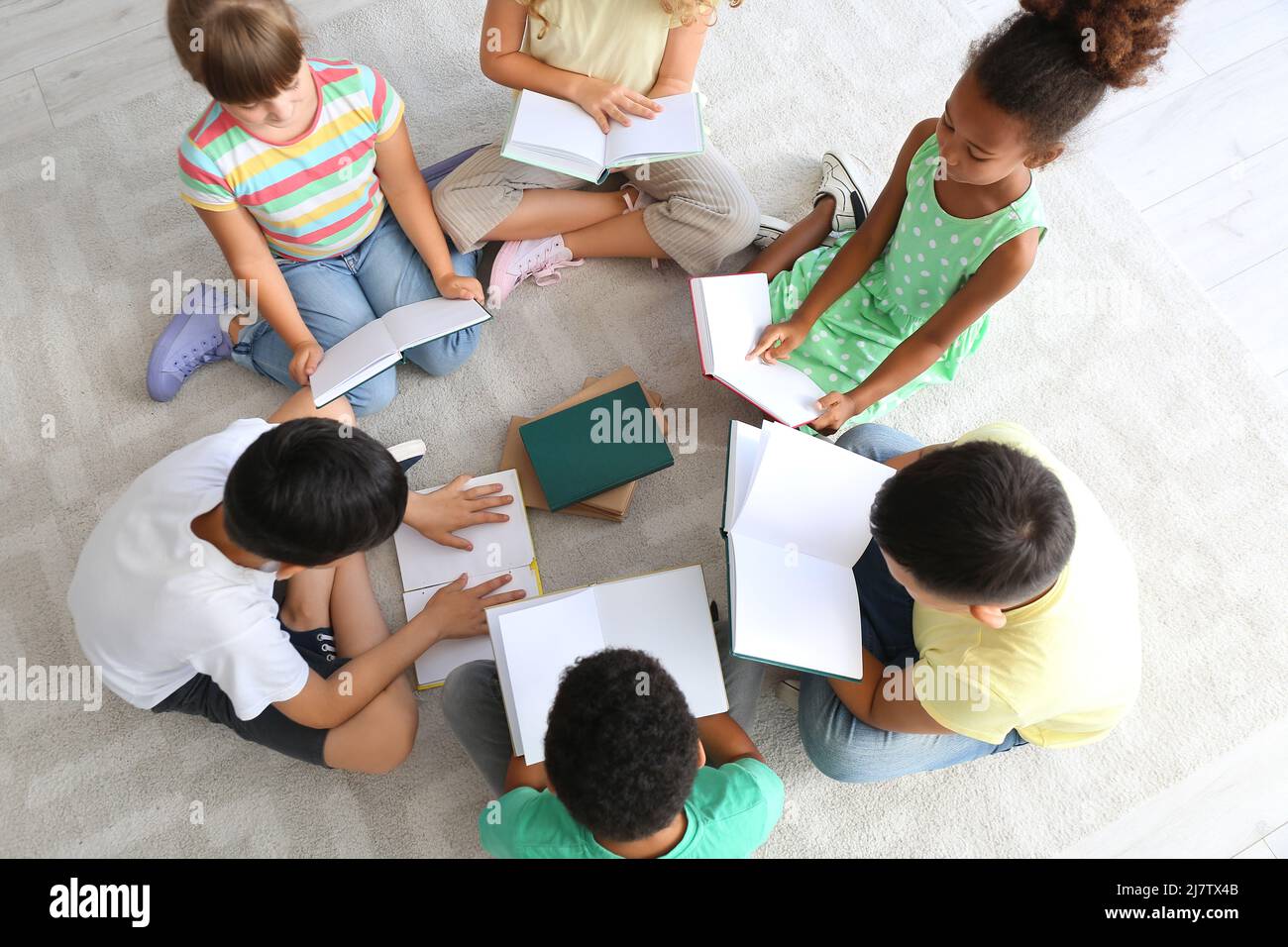 Little children reading books on floor Stock Photo - Alamy