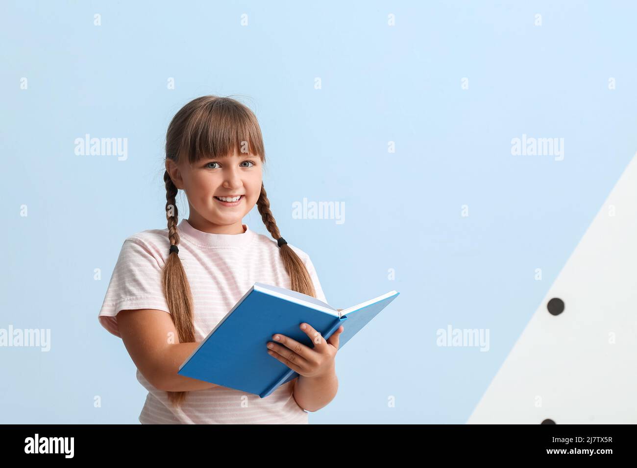 Little girl with braids reading book on blue background Stock Photo - Alamy