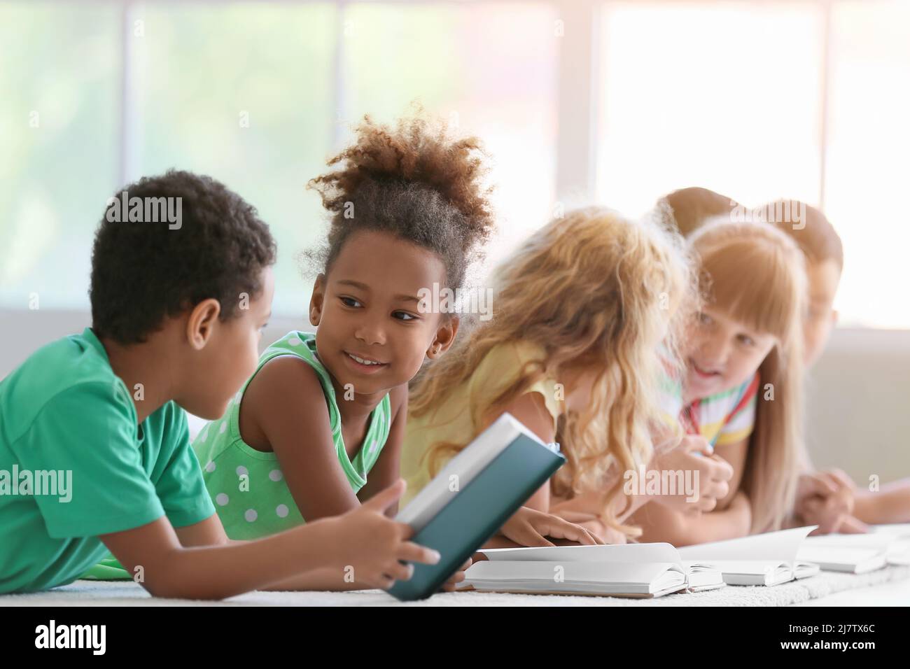 Cute little children reading books on floor in classroom Stock Photo ...