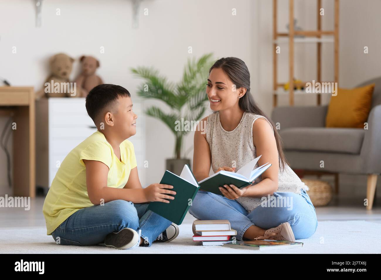 Little Asian boy reading books with his teacher in classroom Stock ...