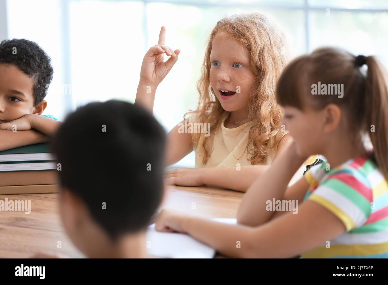 Little redhead girl asking question during literature lesson in ...