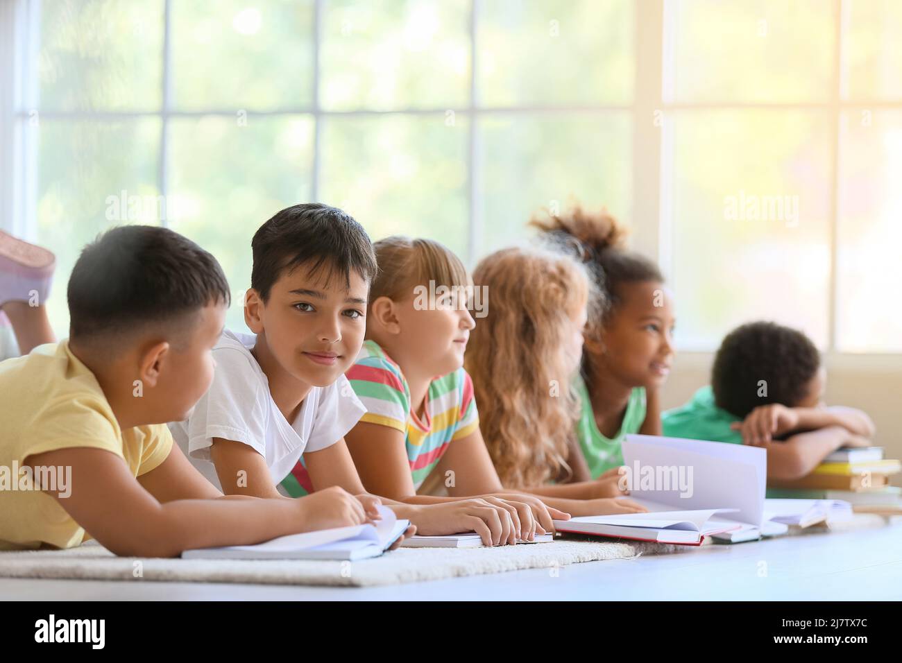 Cute little children reading books on floor in classroom Stock Photo ...