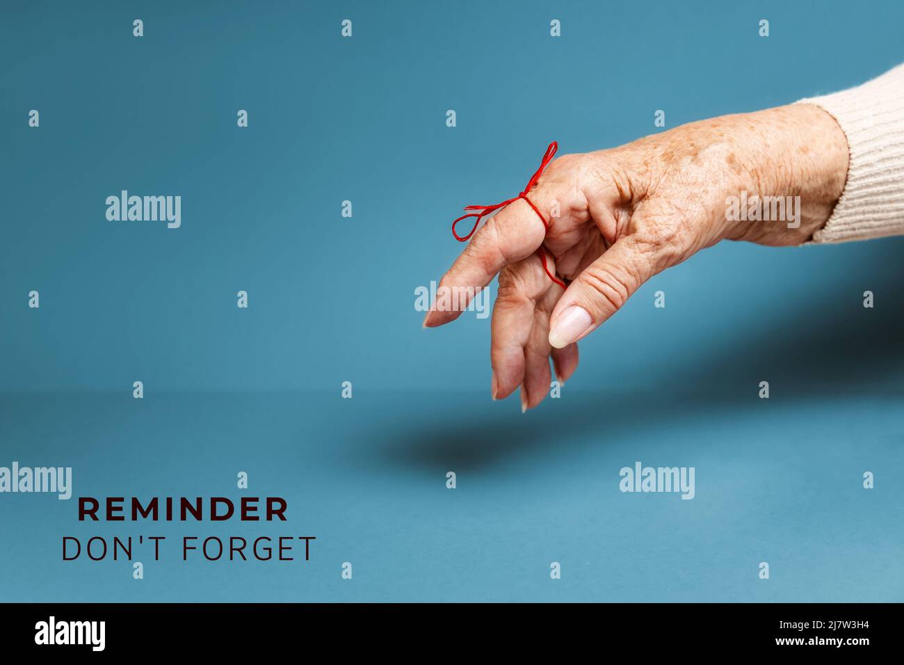 Reminder. Hand of a senior woman with a red thread tied on her index ...