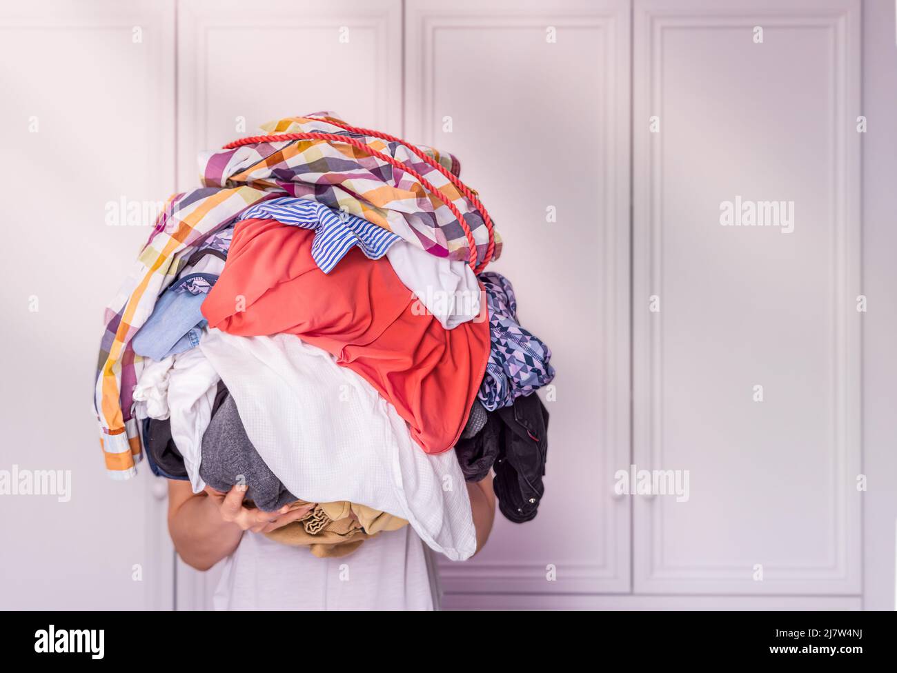 woman holds a lot of crumpled clothes in her hands, white background ...