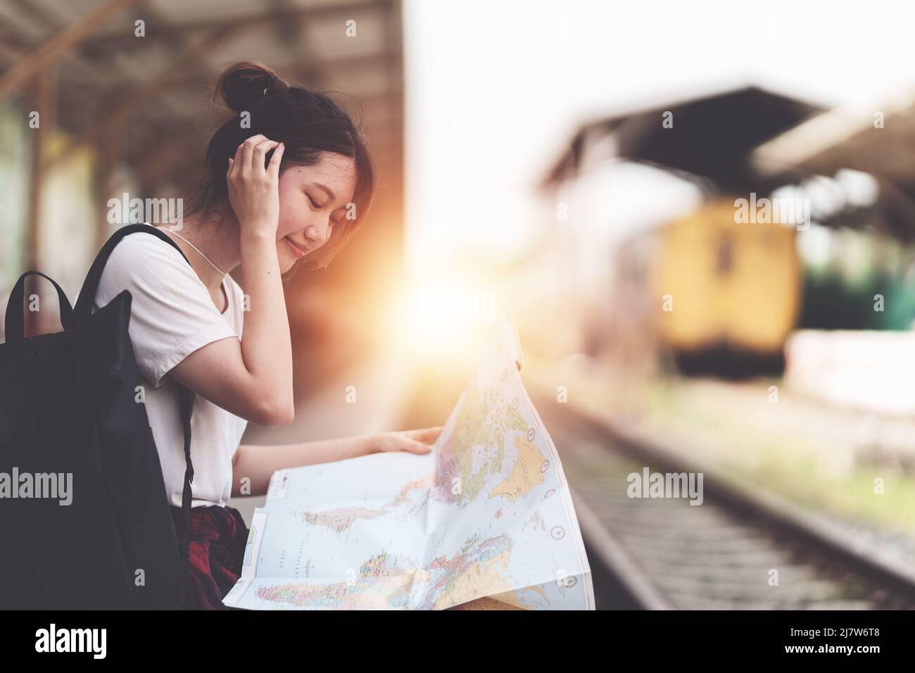 Young traveler woman looking on maps planning trip at train station ...