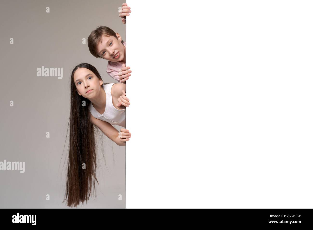 Surprised teenagers peeking out at edge with copy space. Portrait cute ...