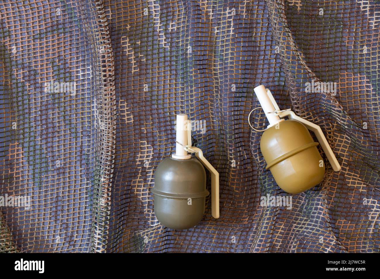 Two hand grenades lie on a camouflage net as a background, military ...