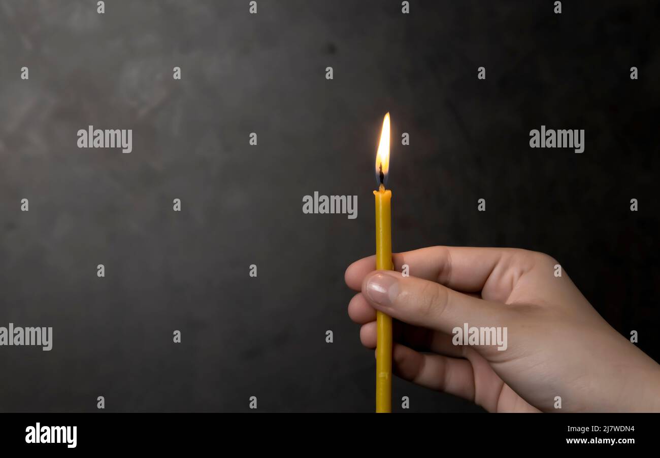 Candle in hand. Female hand holding a burning candle. On a black ...