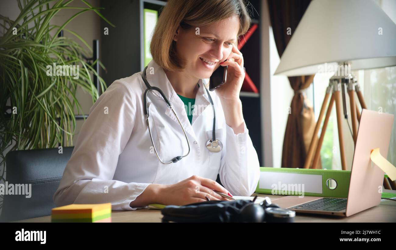 Smiling female doctor talking on phone at workplace in clinic Stock ...