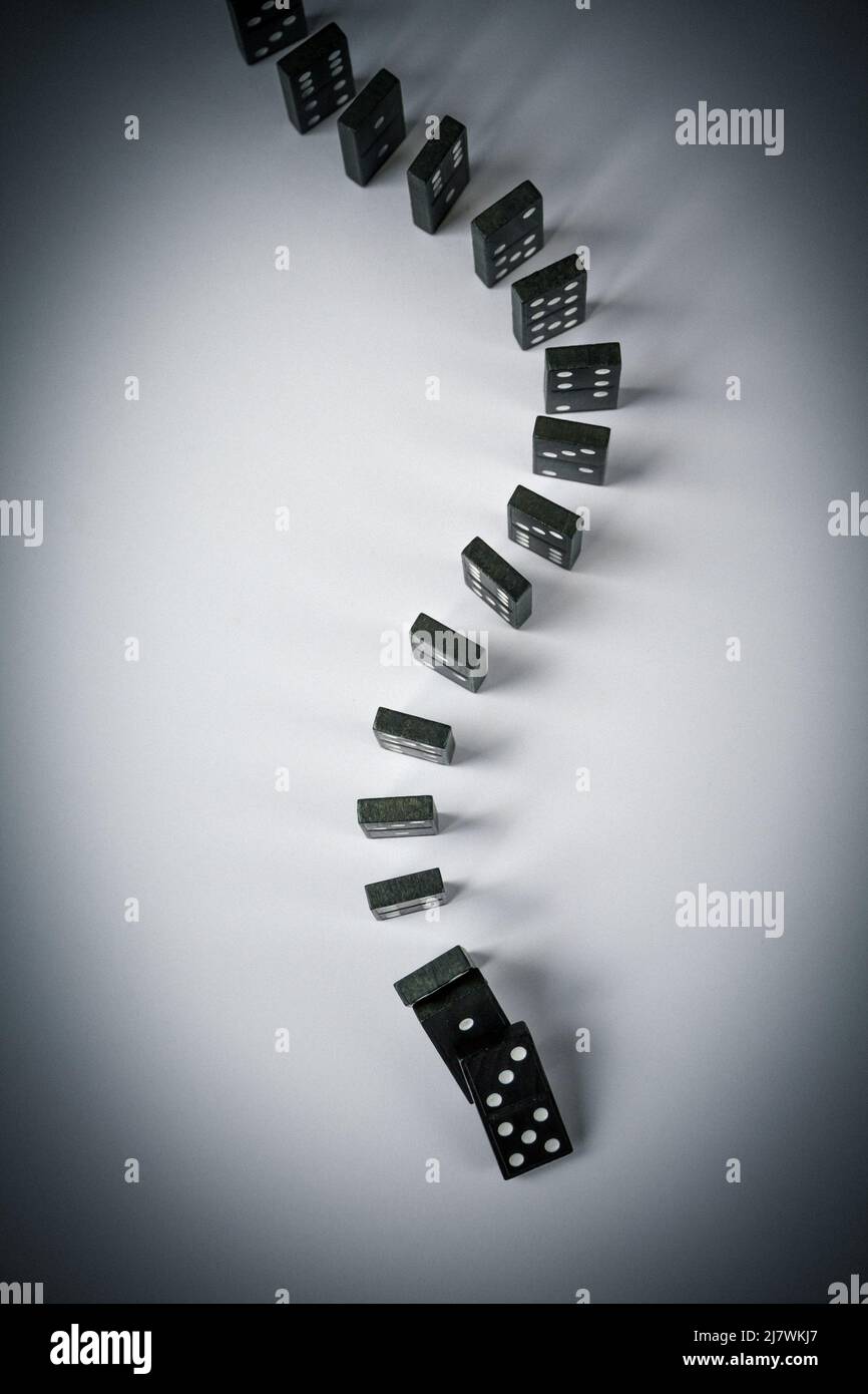 Black dominoes chain on a white table background. Domino effect concept ...