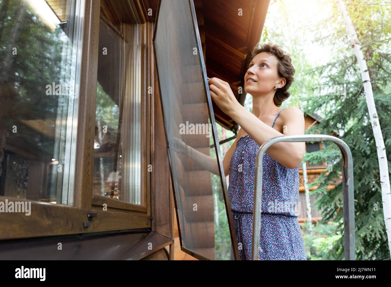 Young adult beautiful slim sporty caucasian woman stand on metal ladder ...