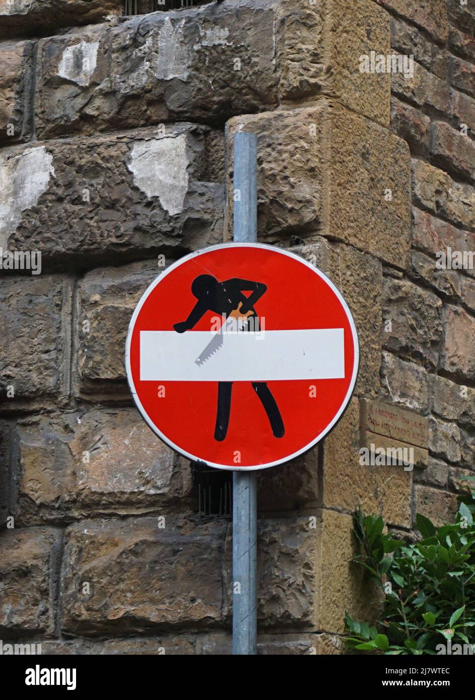 Funny "no entry" street sign of man cutting the white dash with a saw ...