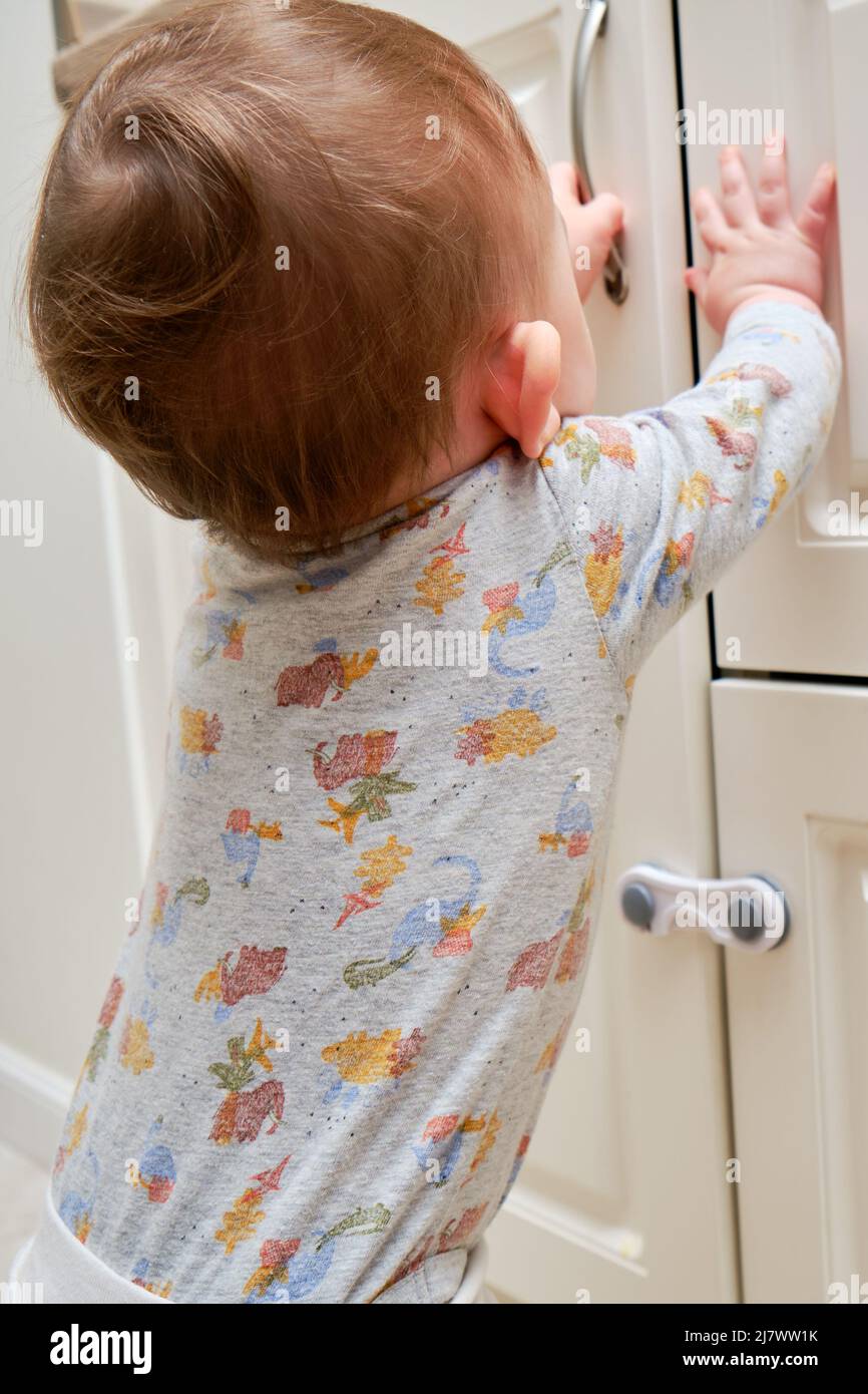 Toddler baby boy rips off a cabinet drawer with his hand. The child ...