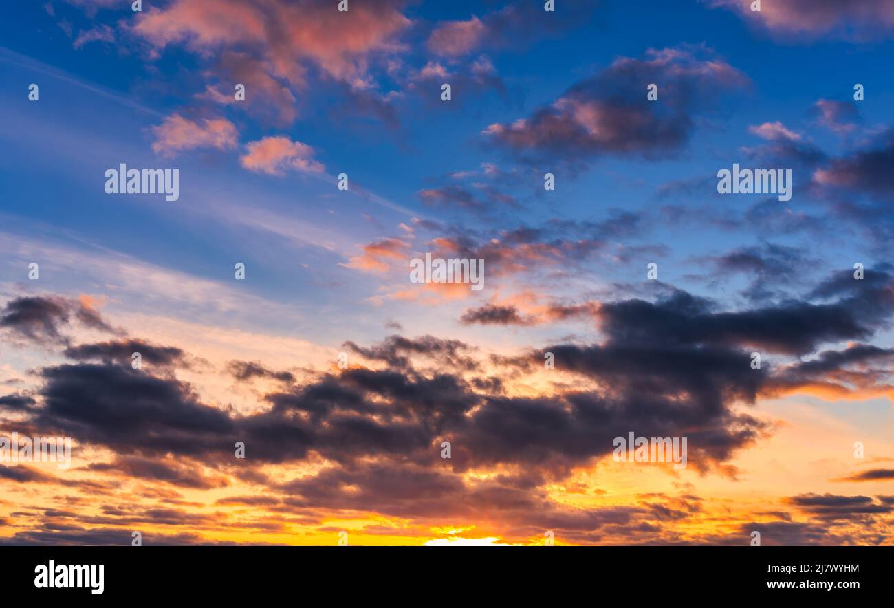 Colorful dramatic clouds lit by a sun against the sunset or sunrise sky ...