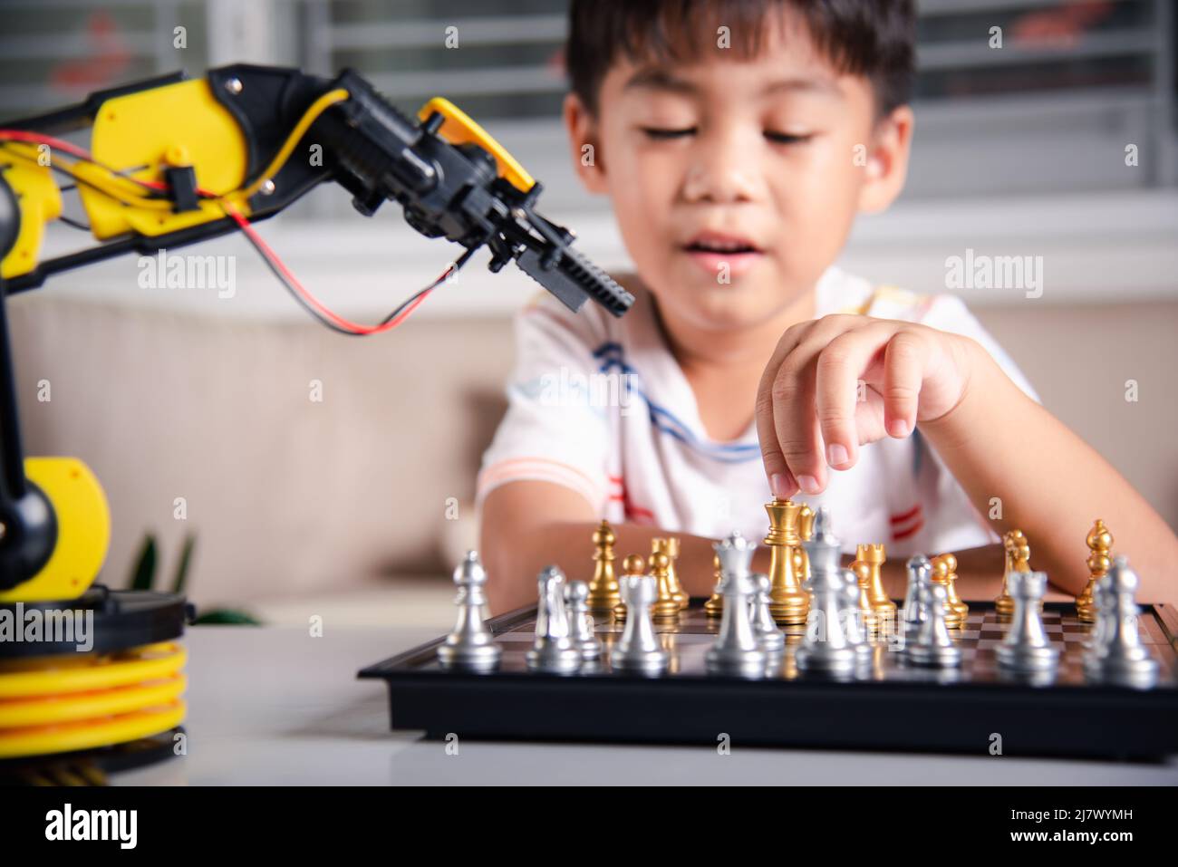 Asian little boy is playing chess with robot machine arm, STEM ...