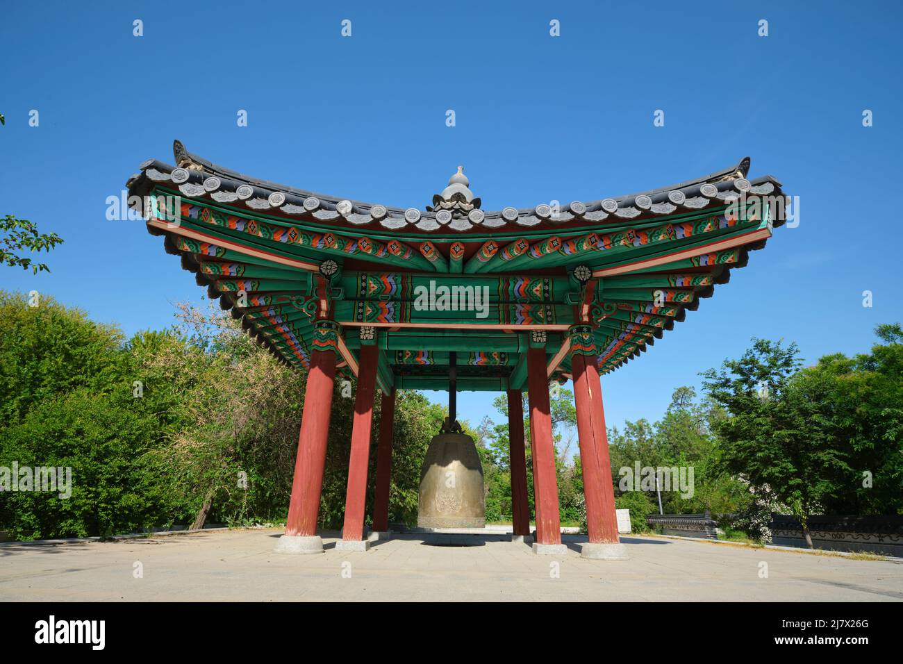 A brightly painted open, small pagoda with huge, large, hanging metal ...