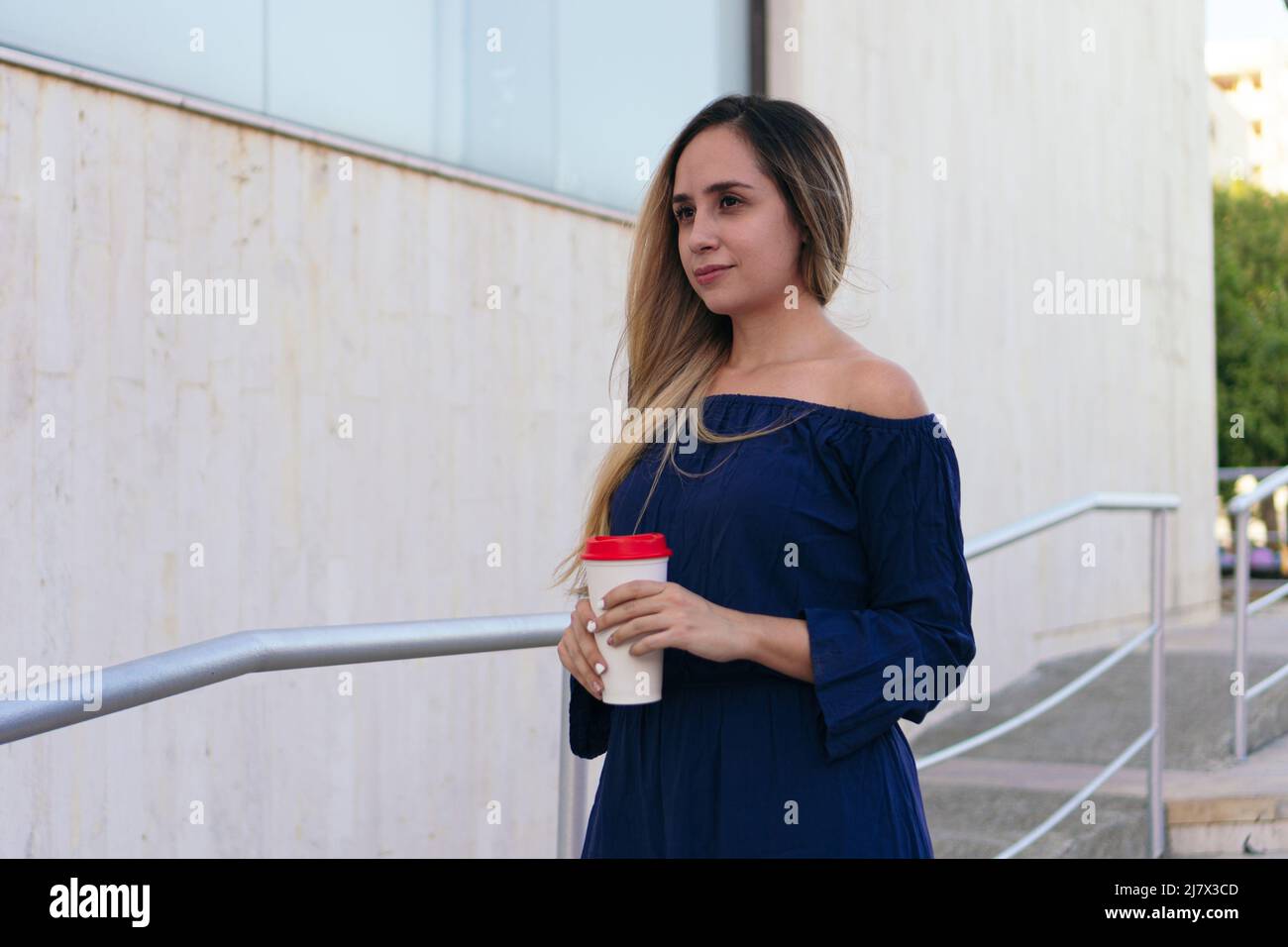 Latin businesswoman with coffee to go cup, office building in the background Stock Photo - Alamy