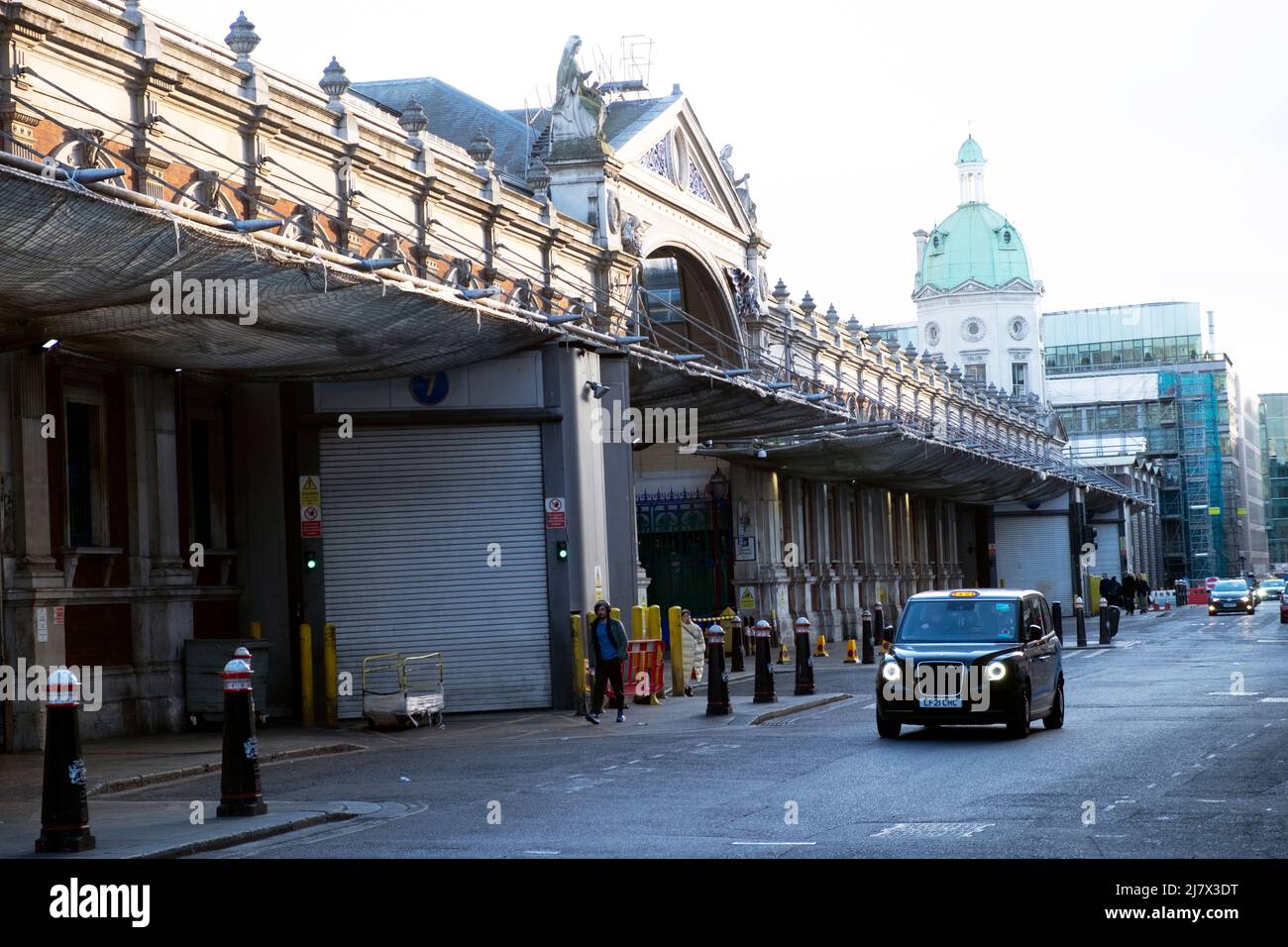 View of Smithfield Market building and black taxi cab driving on ...