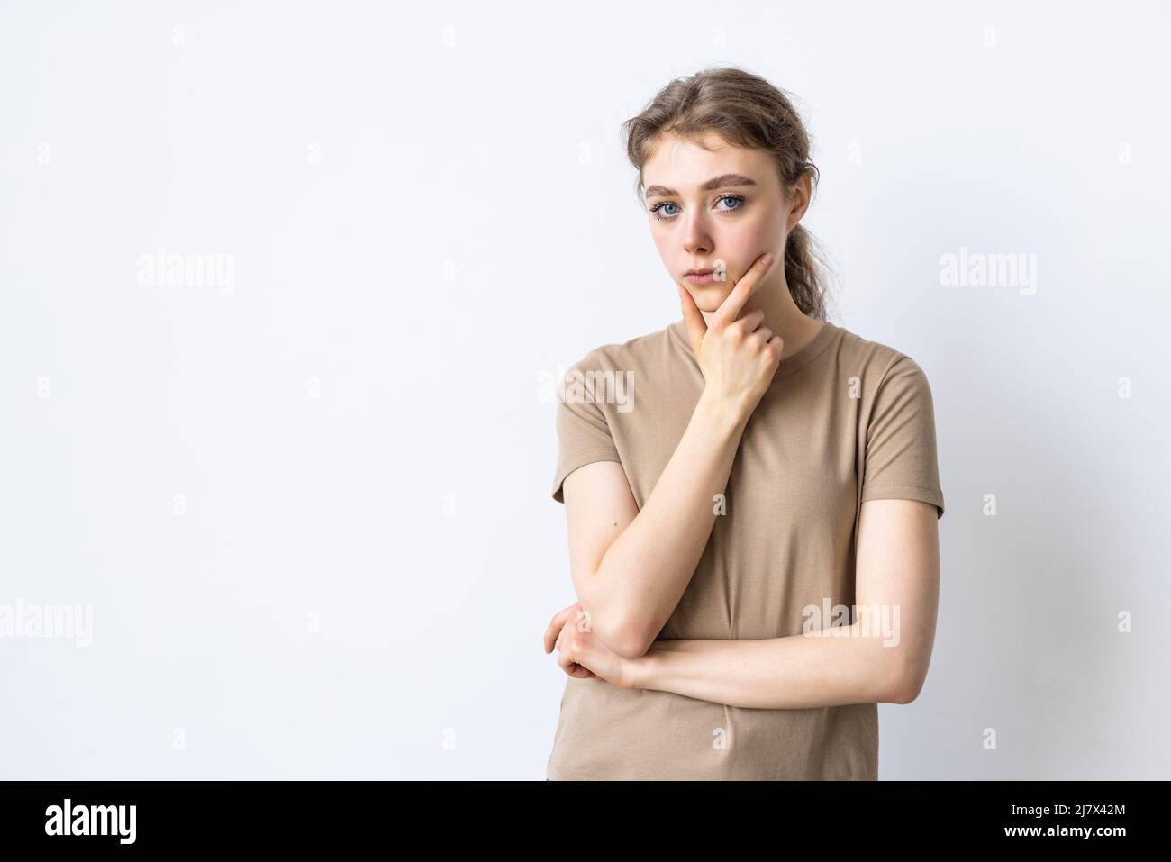 Young beautiful woman thinking looking to the side at blank copy space ...