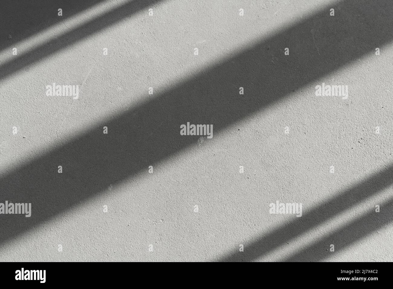 Shadows of window lines on a concrete stone wall in a bright room ...